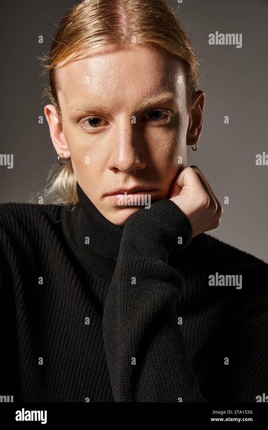portrait of young non binary person in black turtleneck with ponytail ...