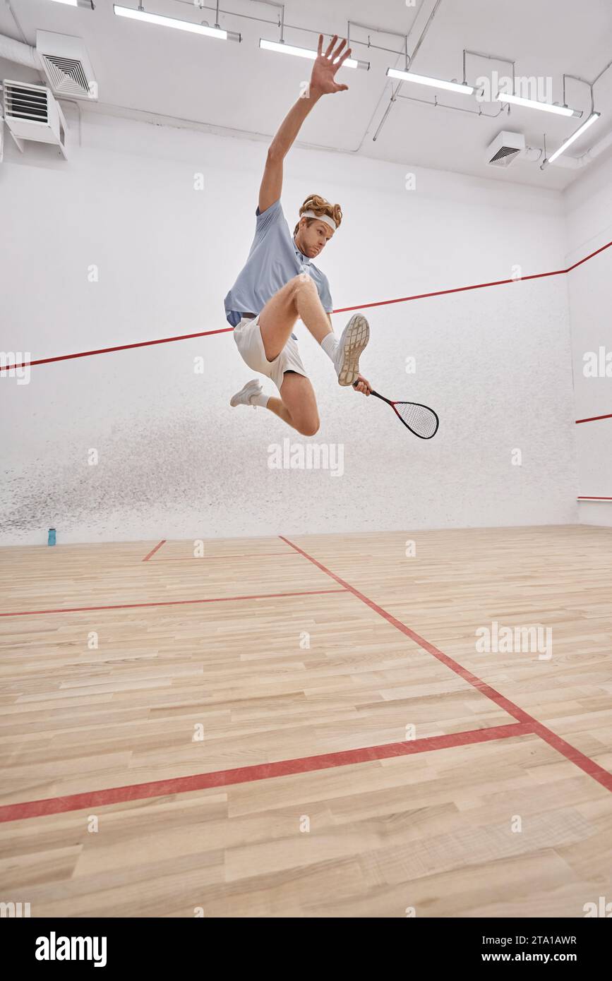 motion and fun, active sportsman holding racquet and jumping while ...