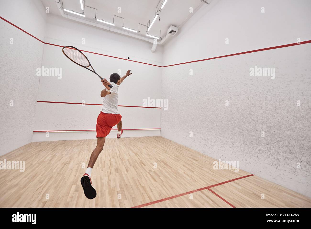 young athletic african american player with racquet jumping and playing ...