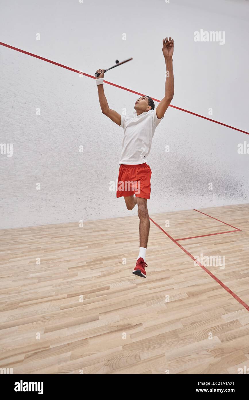 motion shot, focused african american sportsman with racquet jumping ...