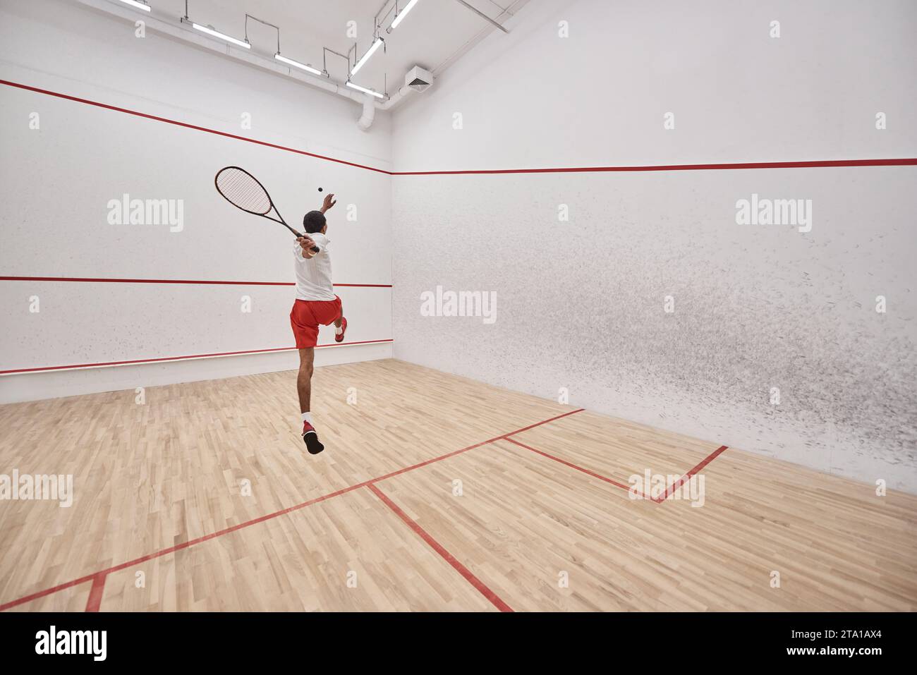young and athletic african american player with racquet jumping and ...
