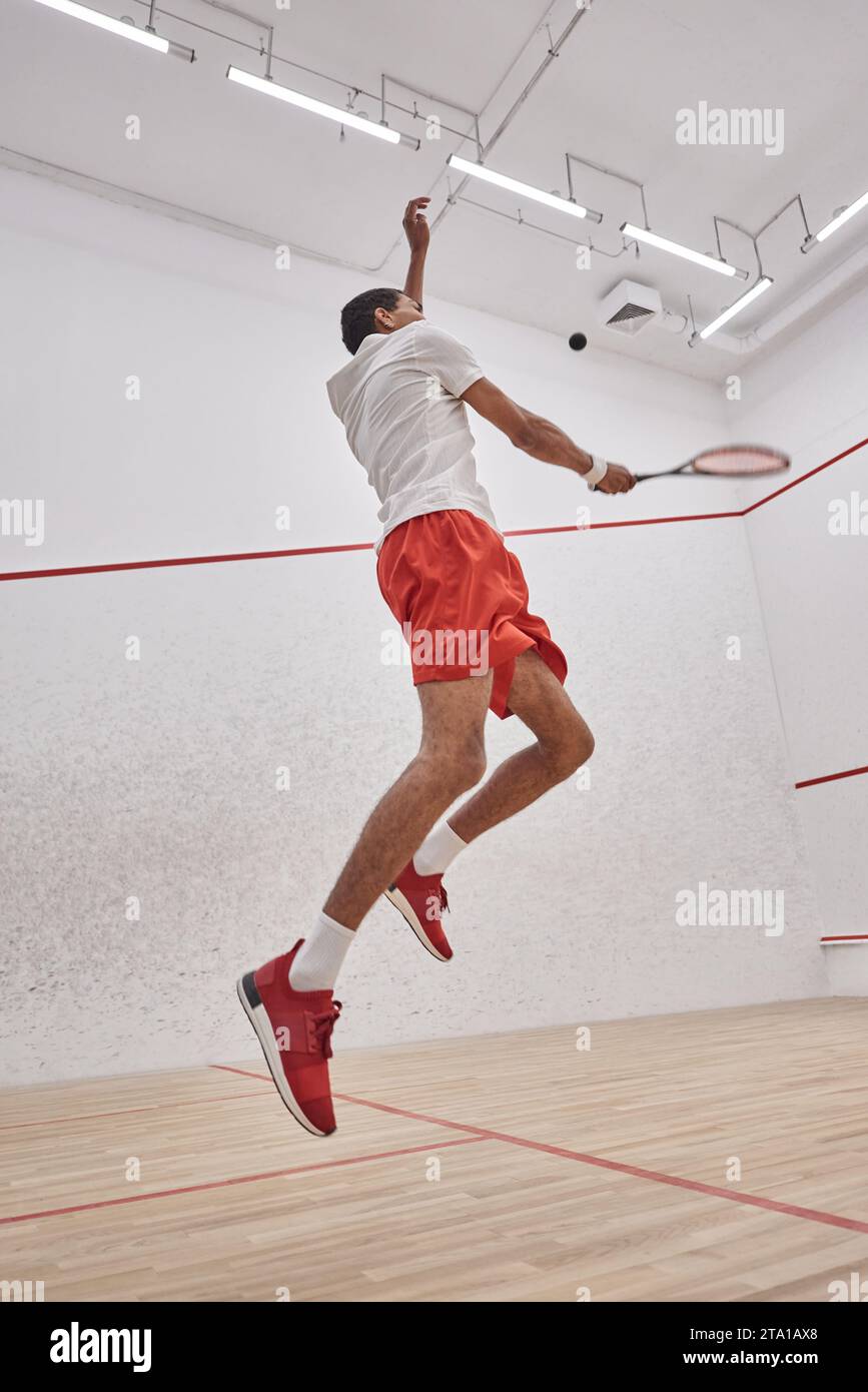 motion photo, active african american sportsman with racquet jumping ...