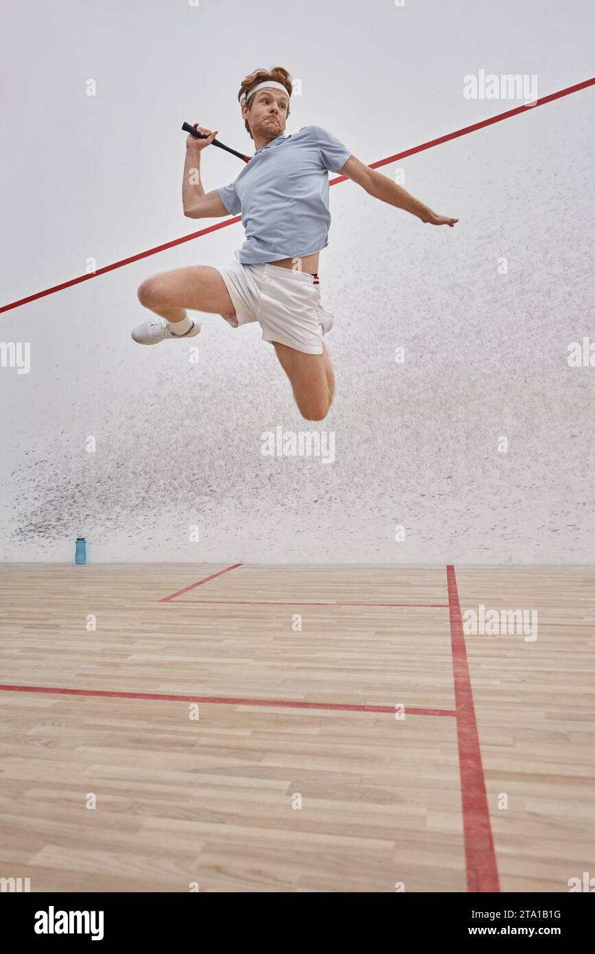 motion shot, active sportsman holding racquet and jumping while playing ...