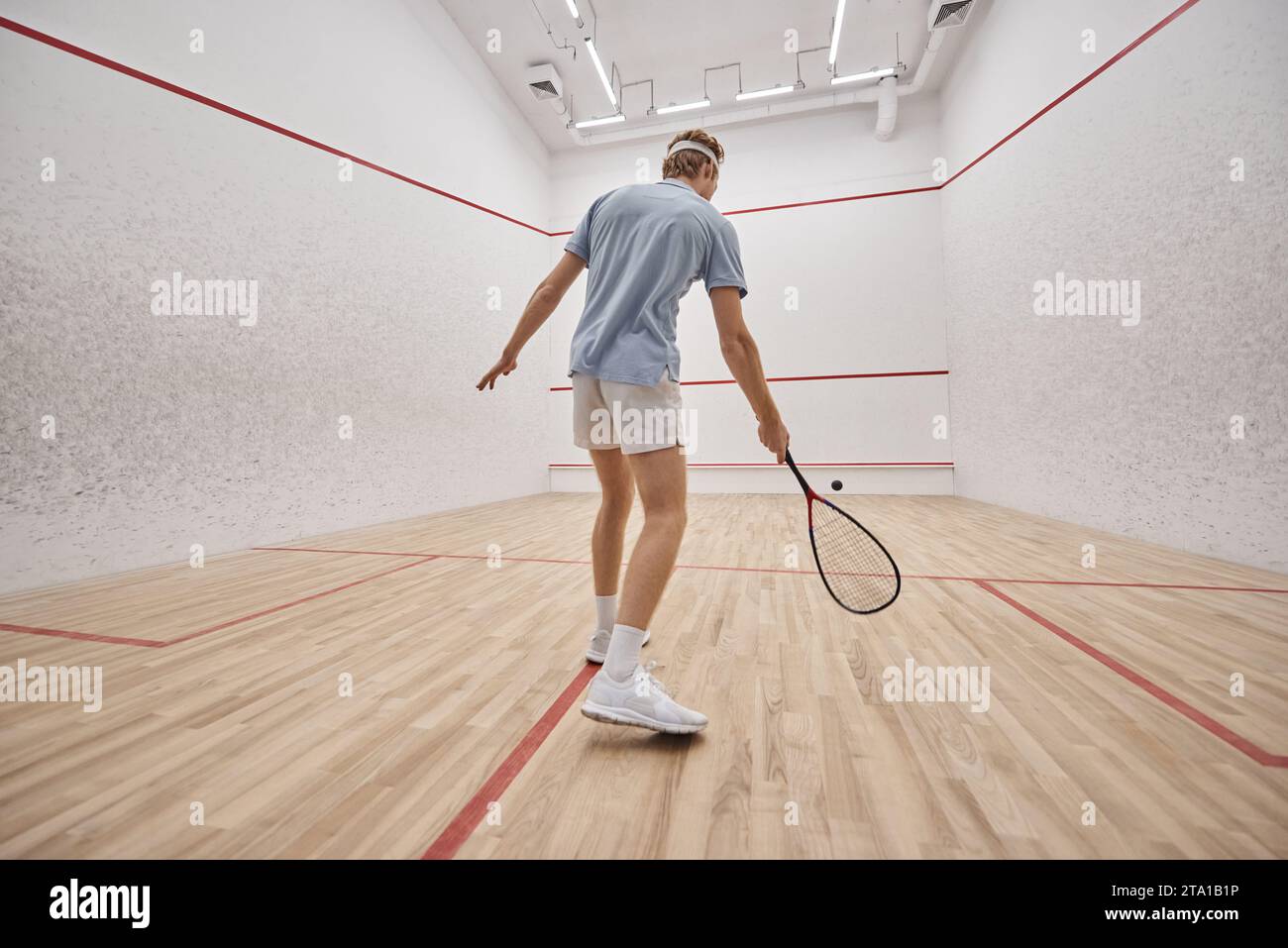athletic redhead sportsman holding racquet and playing squash inside of ...