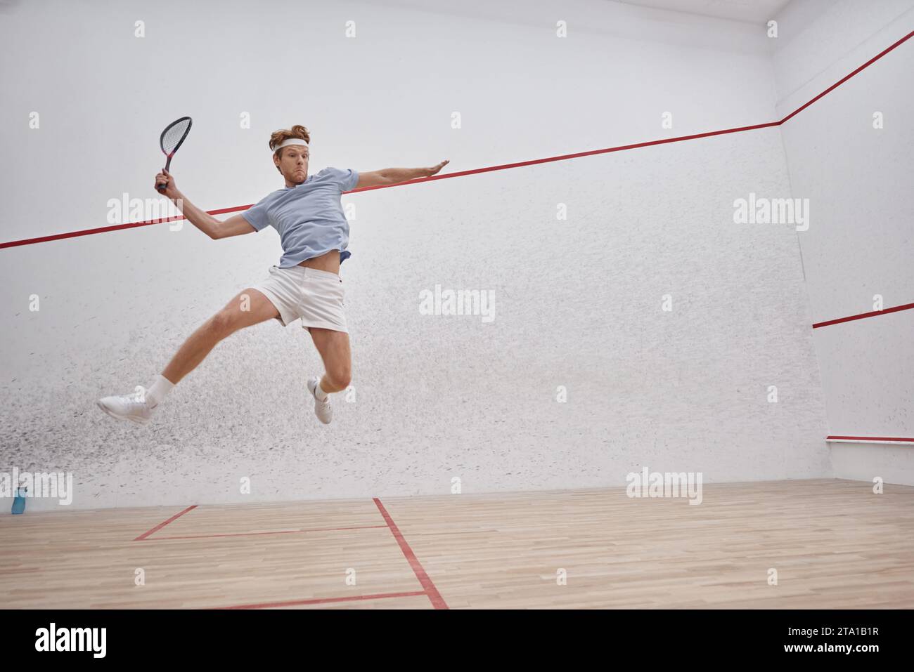 motion shot, athletic sportsman holding racquet and jumping while ...