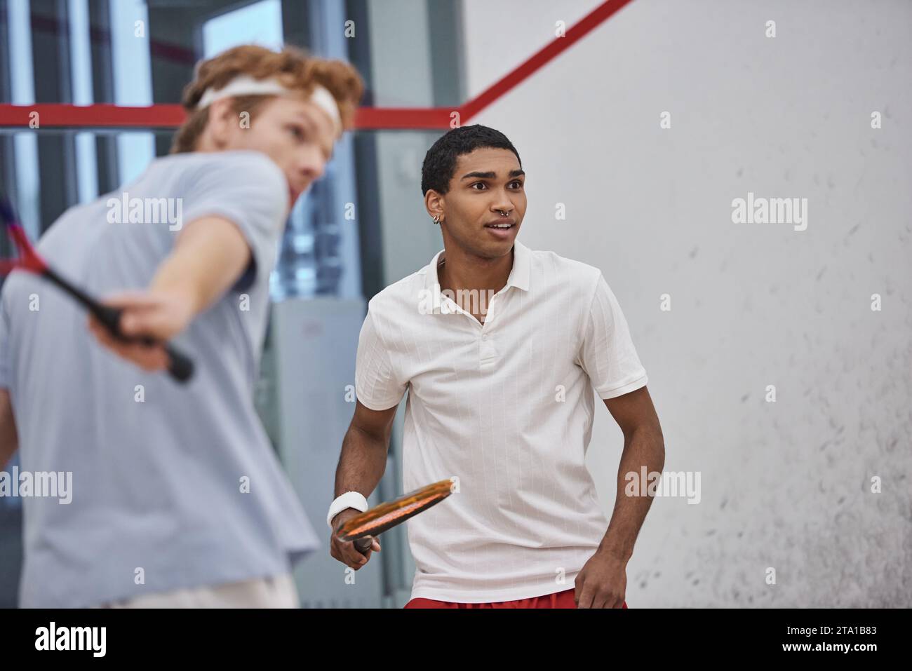 excited african american man holding squash racquet while playing with ...