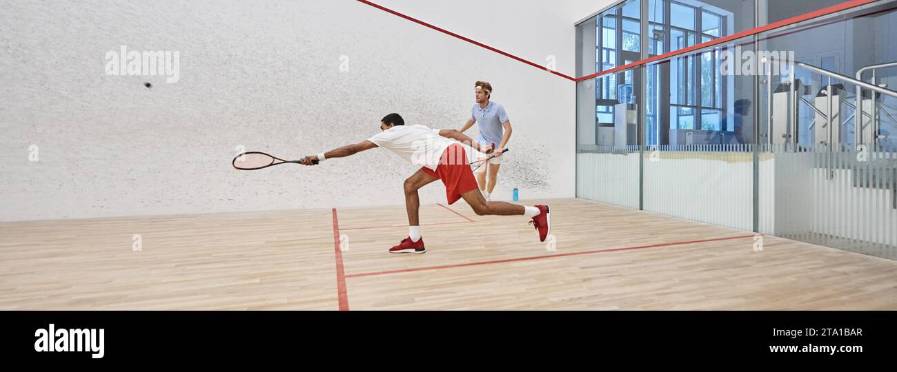 dynamic multicultural sportsmen playing squash together inside of court ...