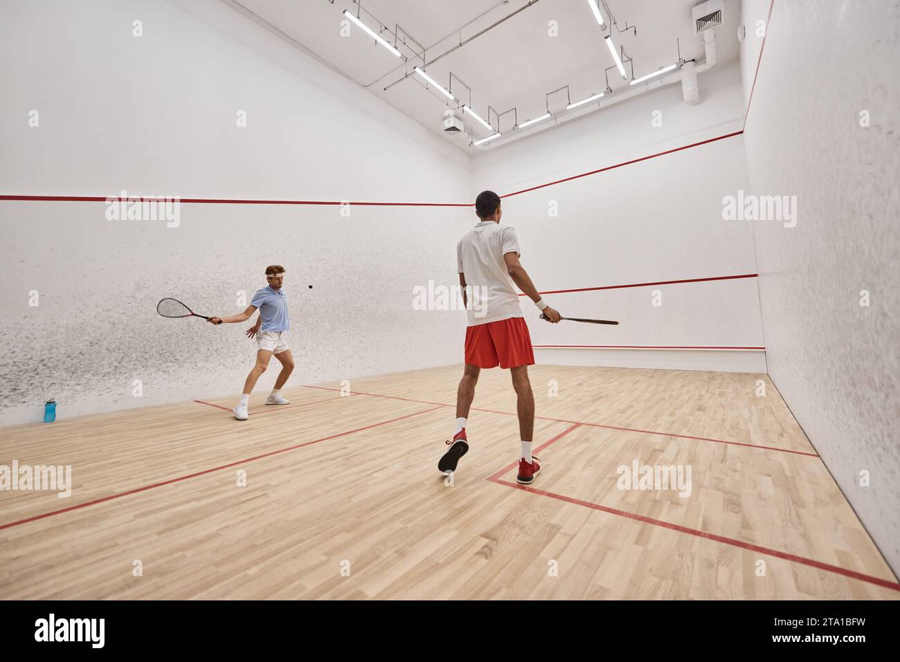 interracial and athletic men in sportswear playing squash together ...