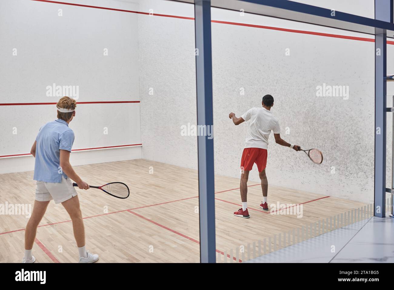 multicultural players in sportswear playing squash together inside of ...
