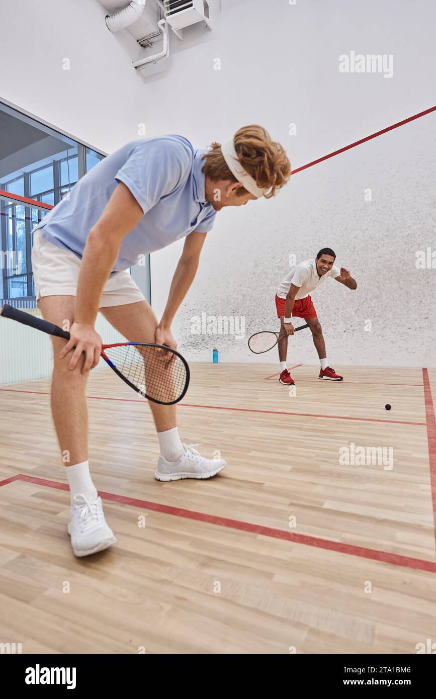 tired interracial players in sportswear breathing heavily after playing ...