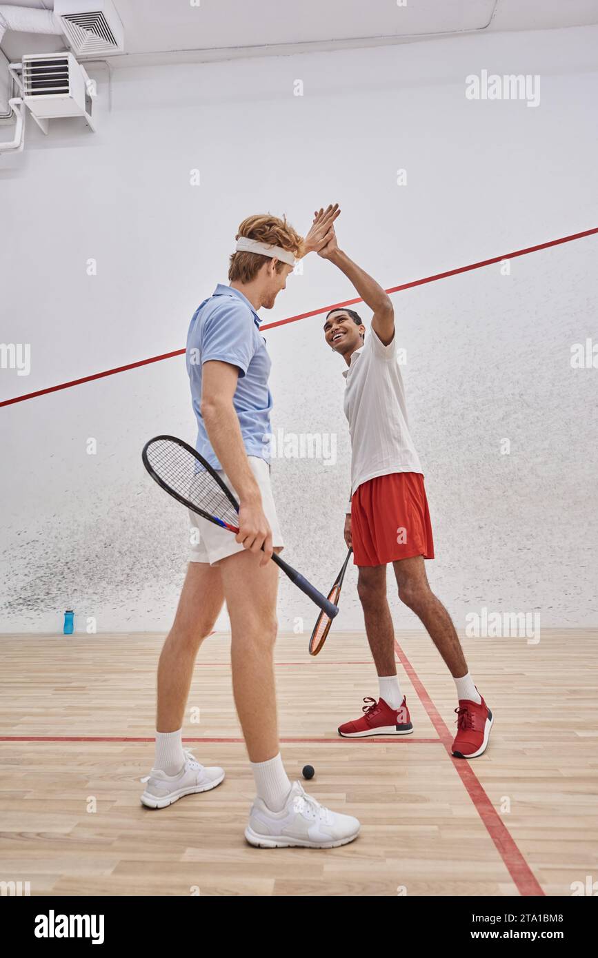 cheerful multicultural friends in sportswear giving high five after ...