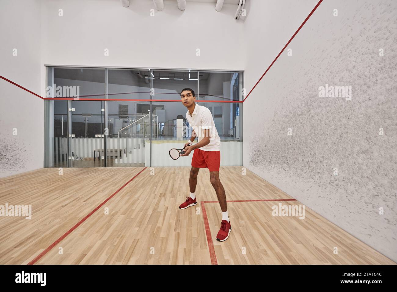 young african american sportsman holding squash ball and racquet while ...