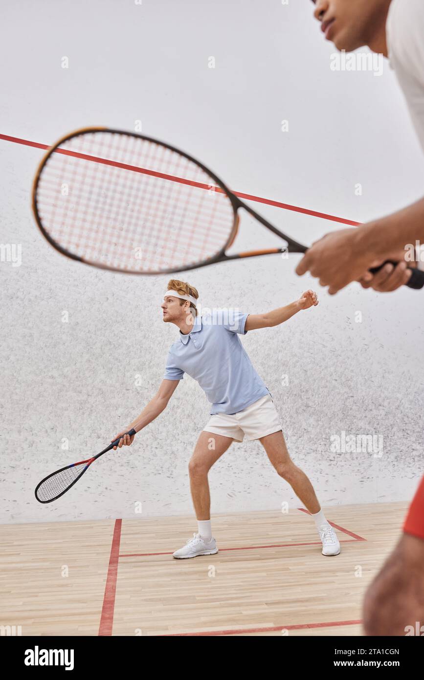 focus on redhead man in sportswear playing with african american friend ...
