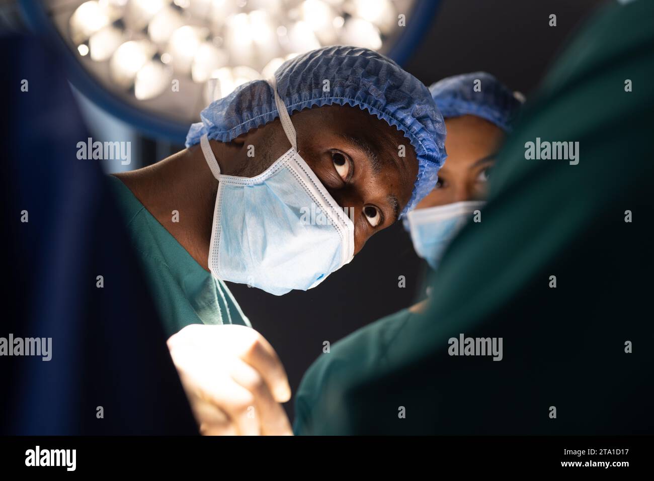 Diverse male and female surgeons with face masks doing surgery in ...