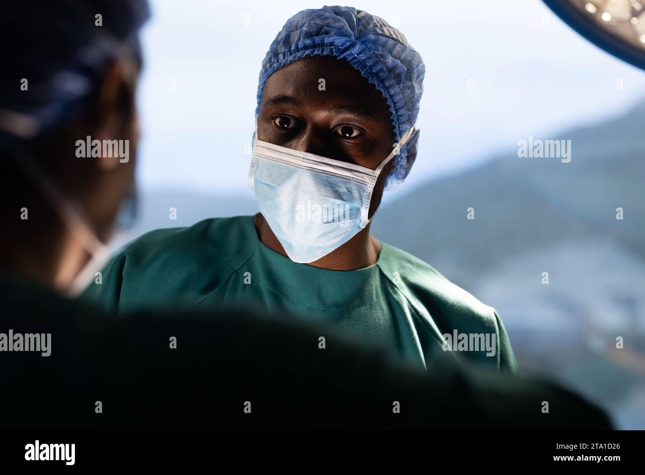African american male surgeon with face mask doing surgery in hospital ...