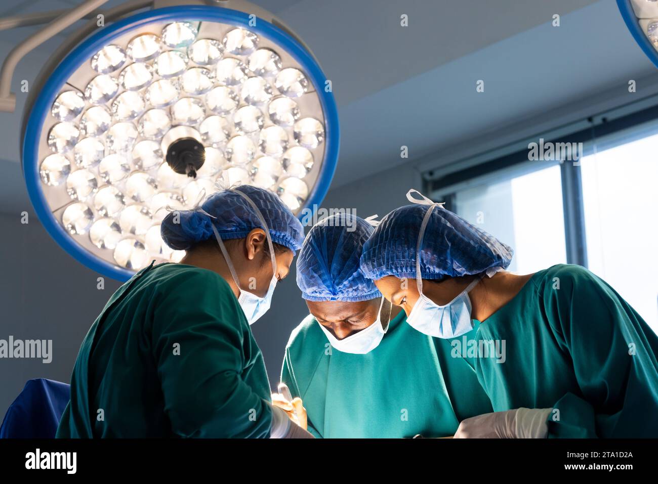 Diverse male and female surgeons with face masks doing surgery in ...
