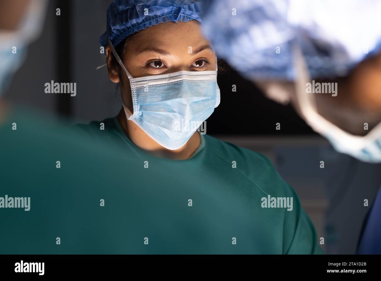Diverse male and female surgeons with face masks doing surgery in ...