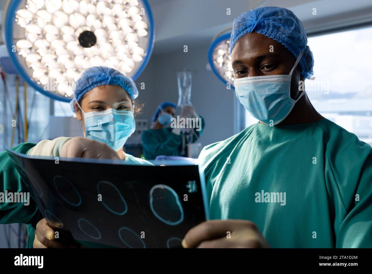 Diverse male and female surgeons with face masks looking at x-rays in ...