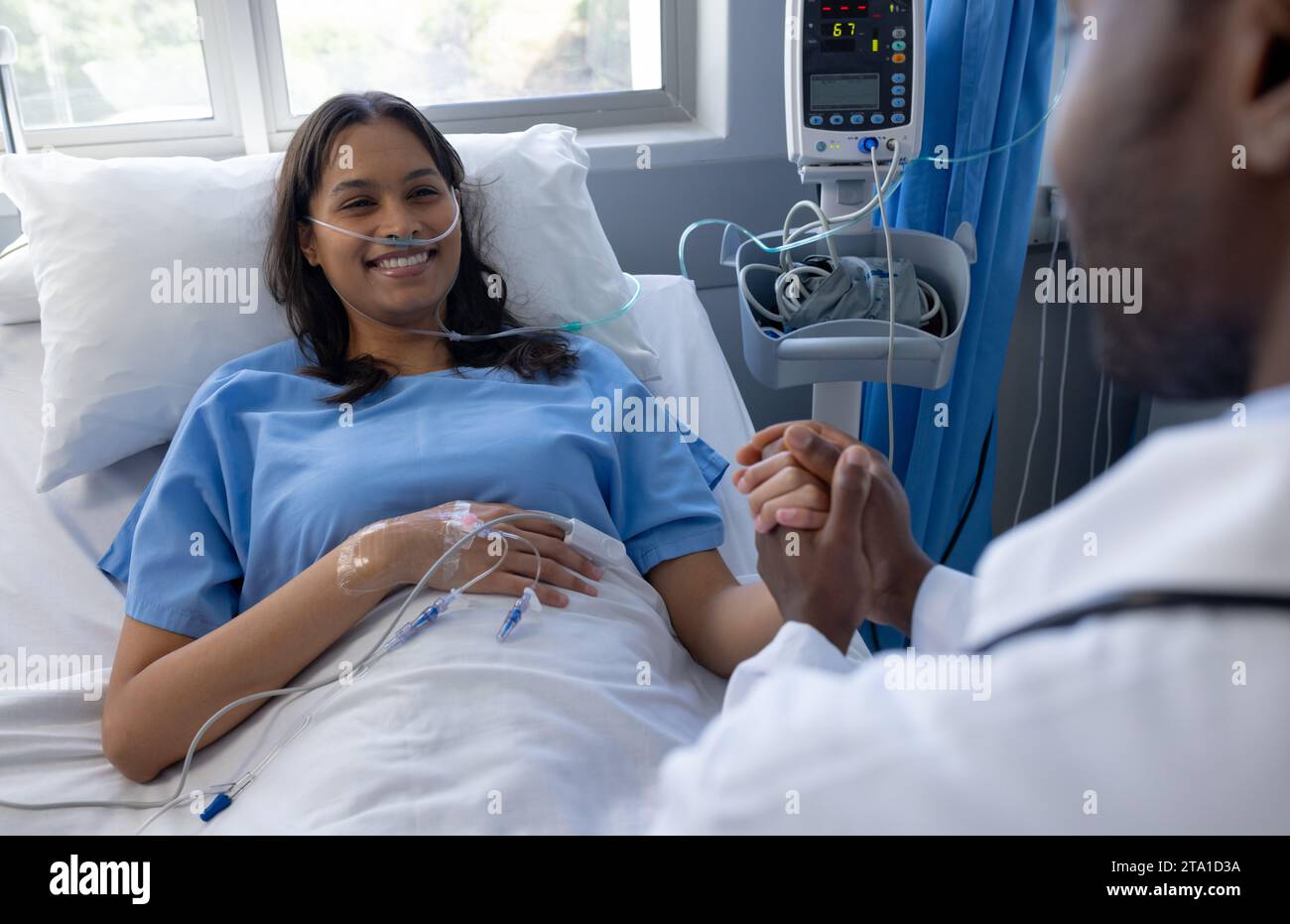 Happy diverse male doctor holding hand of female patient with iv drip ...