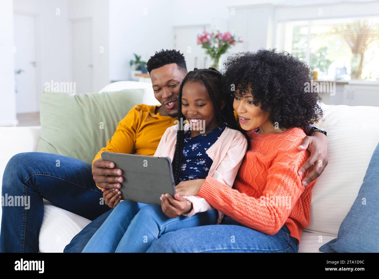 Happy african american family sitting on couch and using tablet at home ...