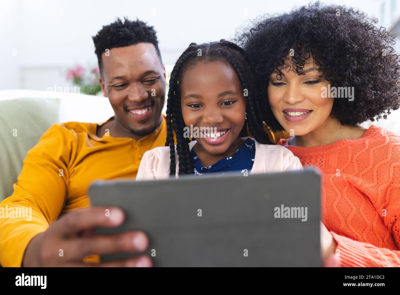 Happy african american family sitting on couch and using tablet at home ...