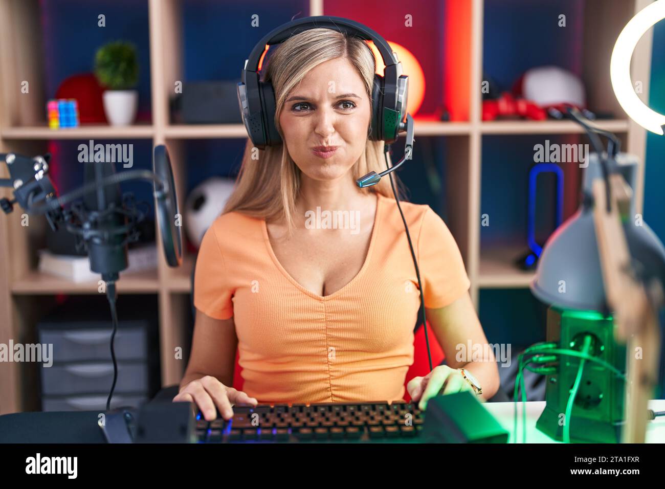 Young woman playing video games puffing cheeks with funny face. mouth ...