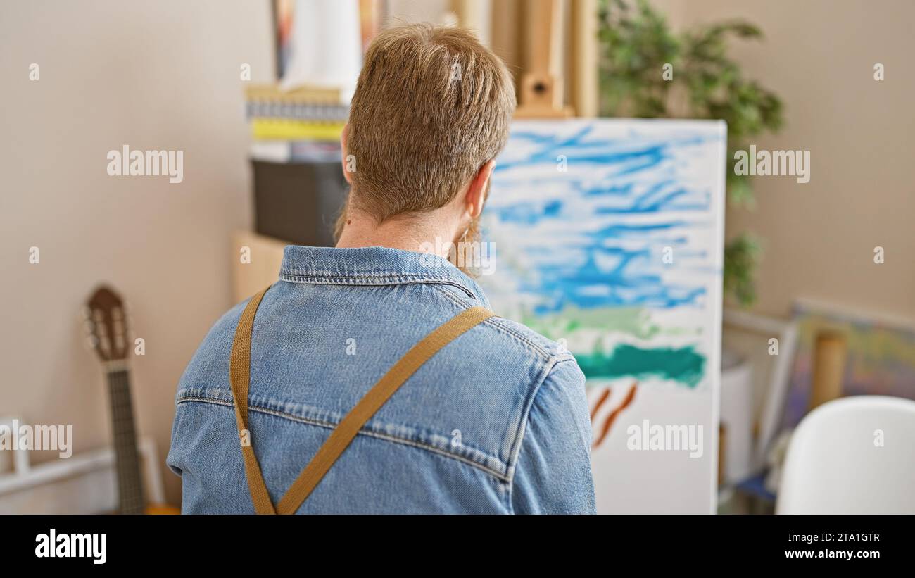 Handsome young redhead man, an ambitious artist, immerse in drawing at the interior art studio ...