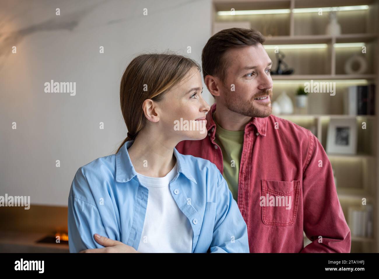 Happy family couple look at window together discussing something ...