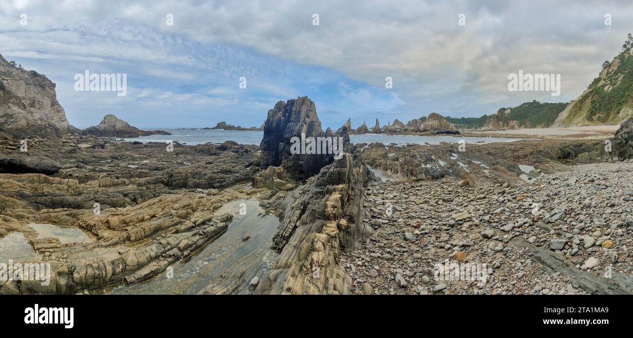 rocky beach with jagged rocks and cliffs under a blue sky with ...