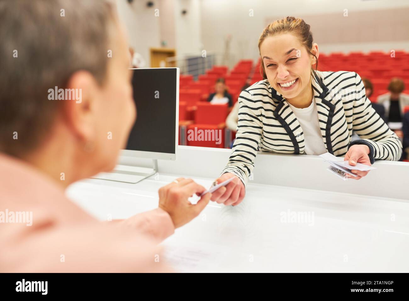 Happy businesswoman giving ID card to speaker sitting on stage during ...