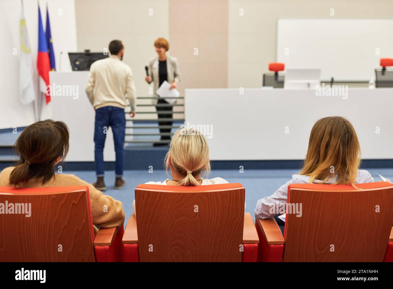Professionals sitting at audience in front of panel during business ...