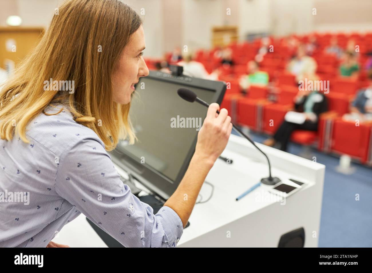 Female speaker on panel at business conference talking with audience ...