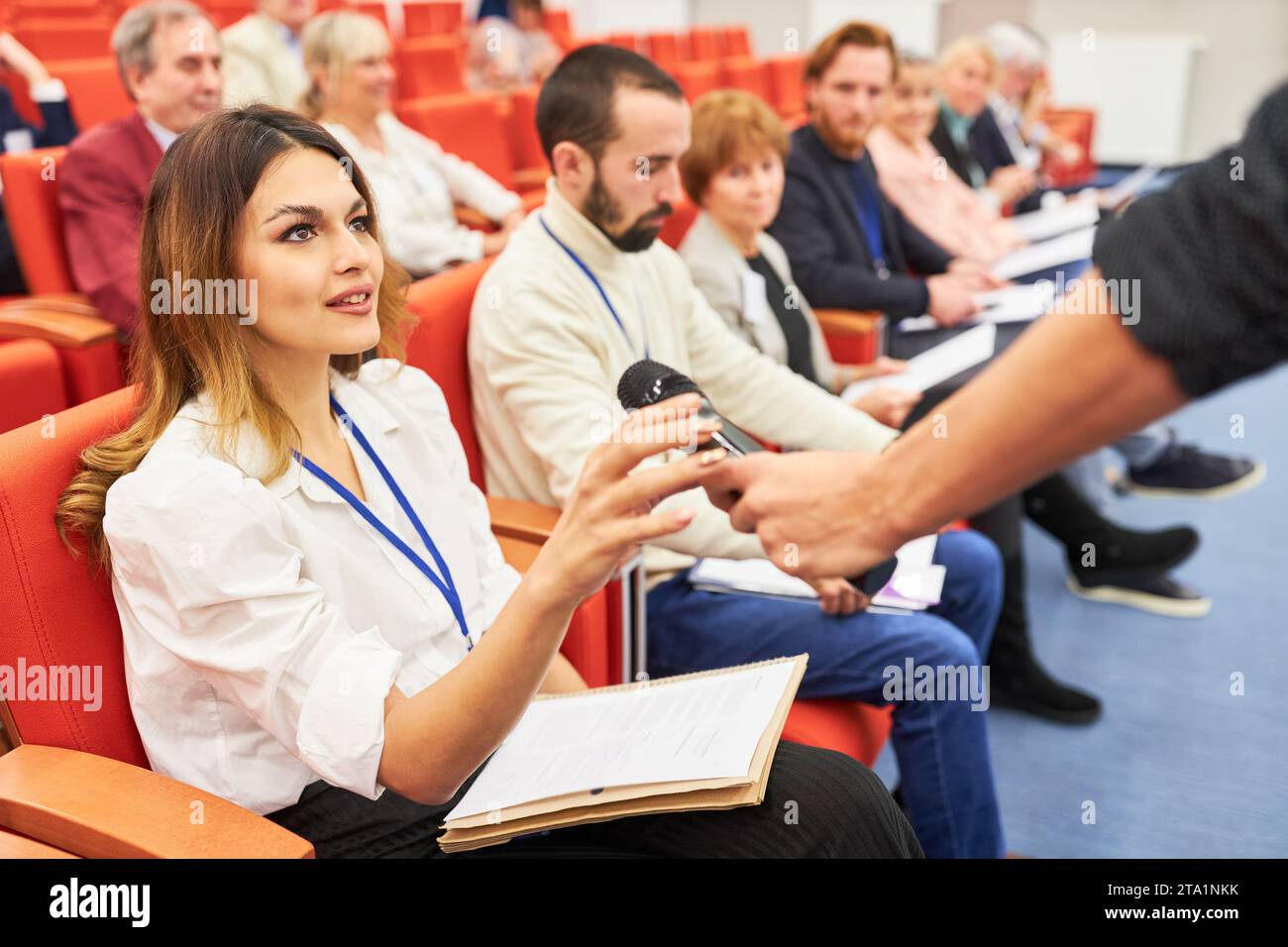 Speaker giving microphone to businesswoman during business conference ...