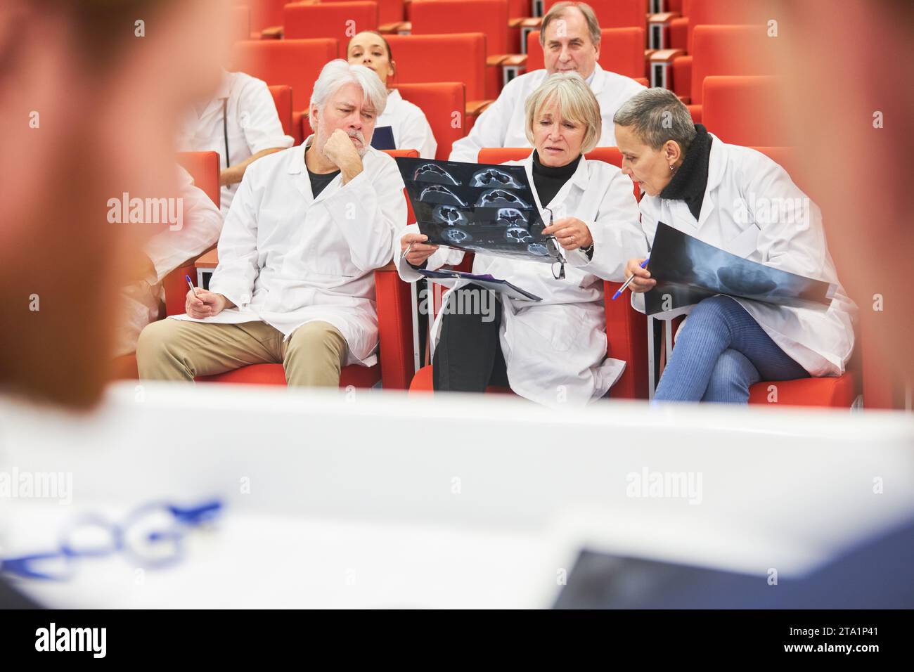 Male and female professionals examining x-ray while sitting in audience ...
