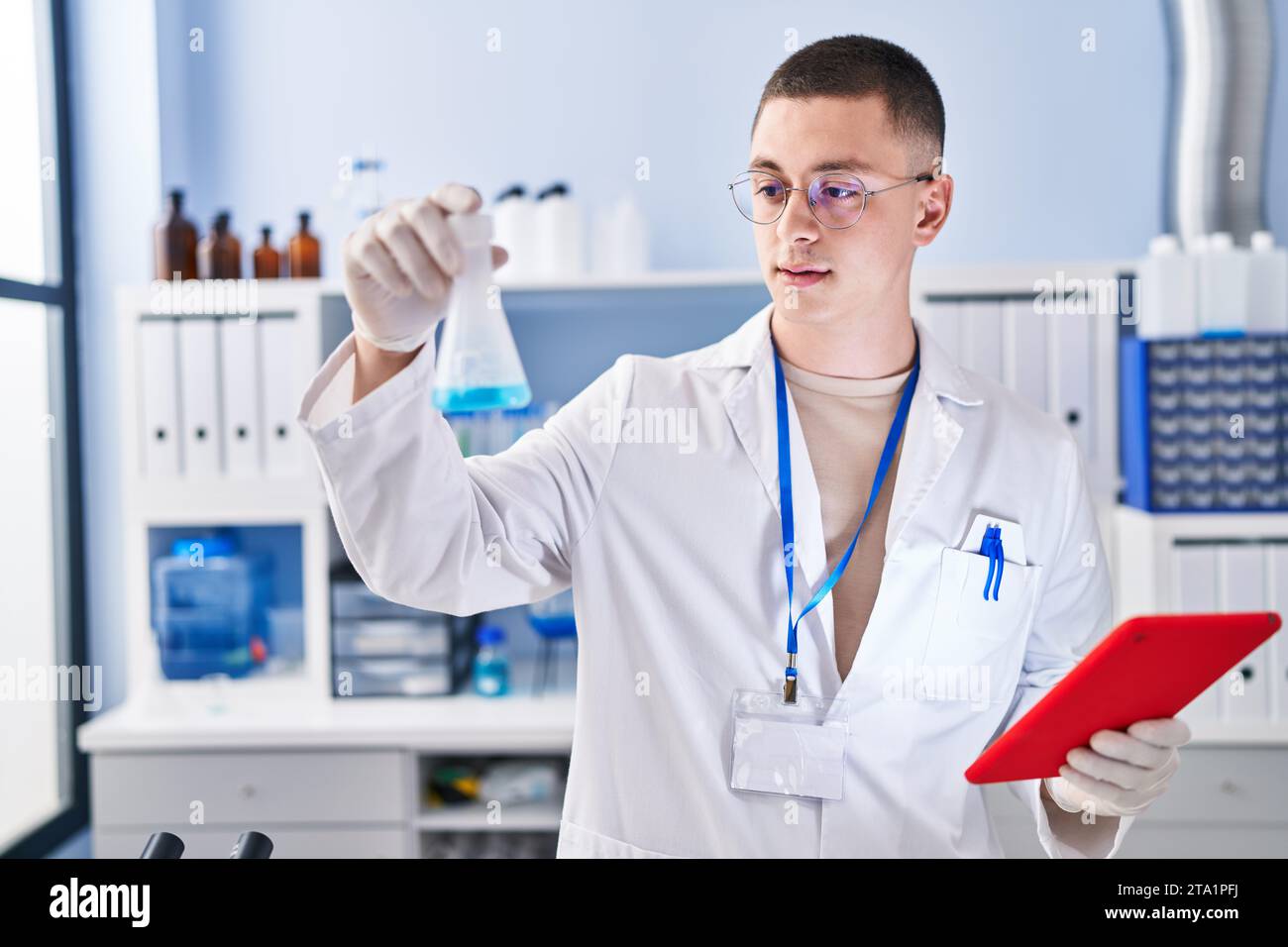 Young hispanic man scientist measuring liquid using touchpad at laboratory Stock Photo - Alamy