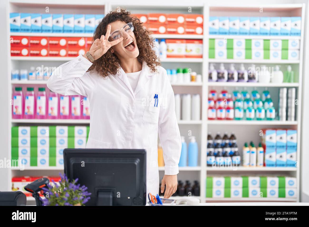 Hispanic woman with curly hair working at pharmacy drugstore doing ...
