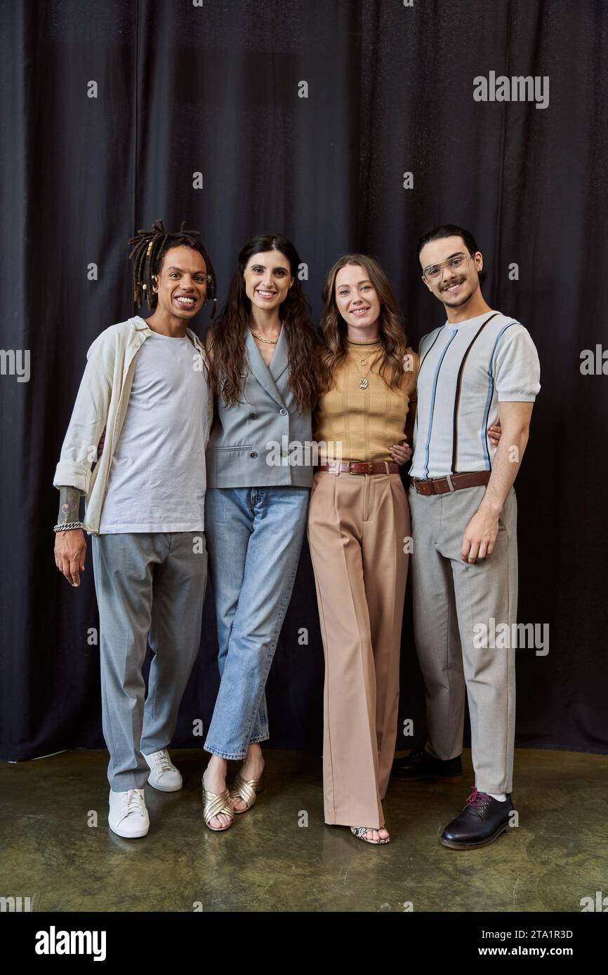 full length of positive multicultural colleagues on black backdrop in ...