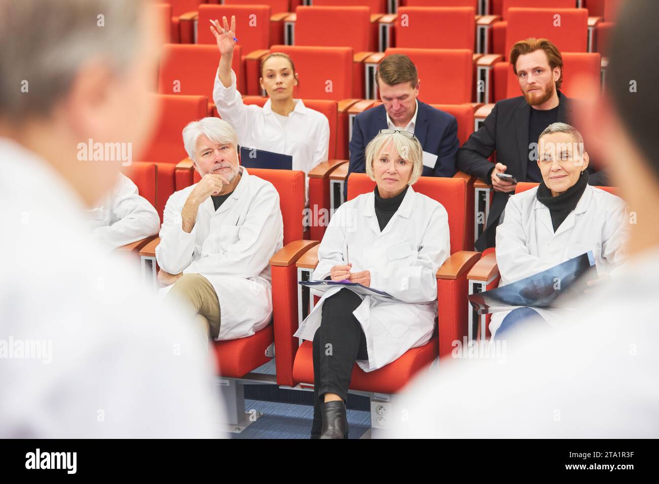 Female doctor in audience of medical conference asking question to ...