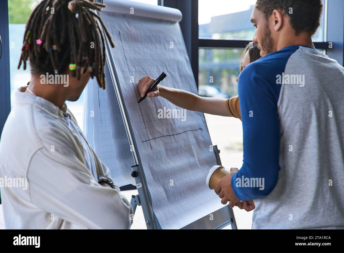 creative woman drawing graphs on flip chart near african american ...