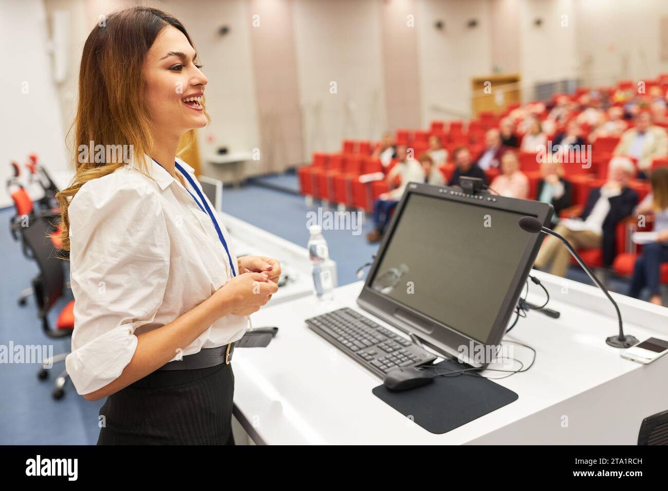 Smiling female speaker on stage talking at business seminar in ...
