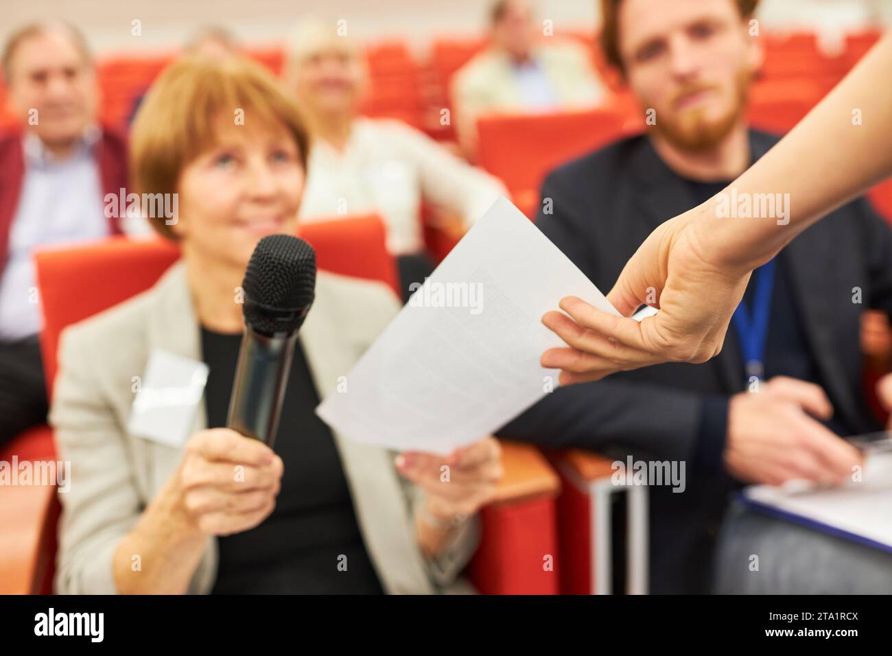 Speaker giving document to audience during business conference at ...