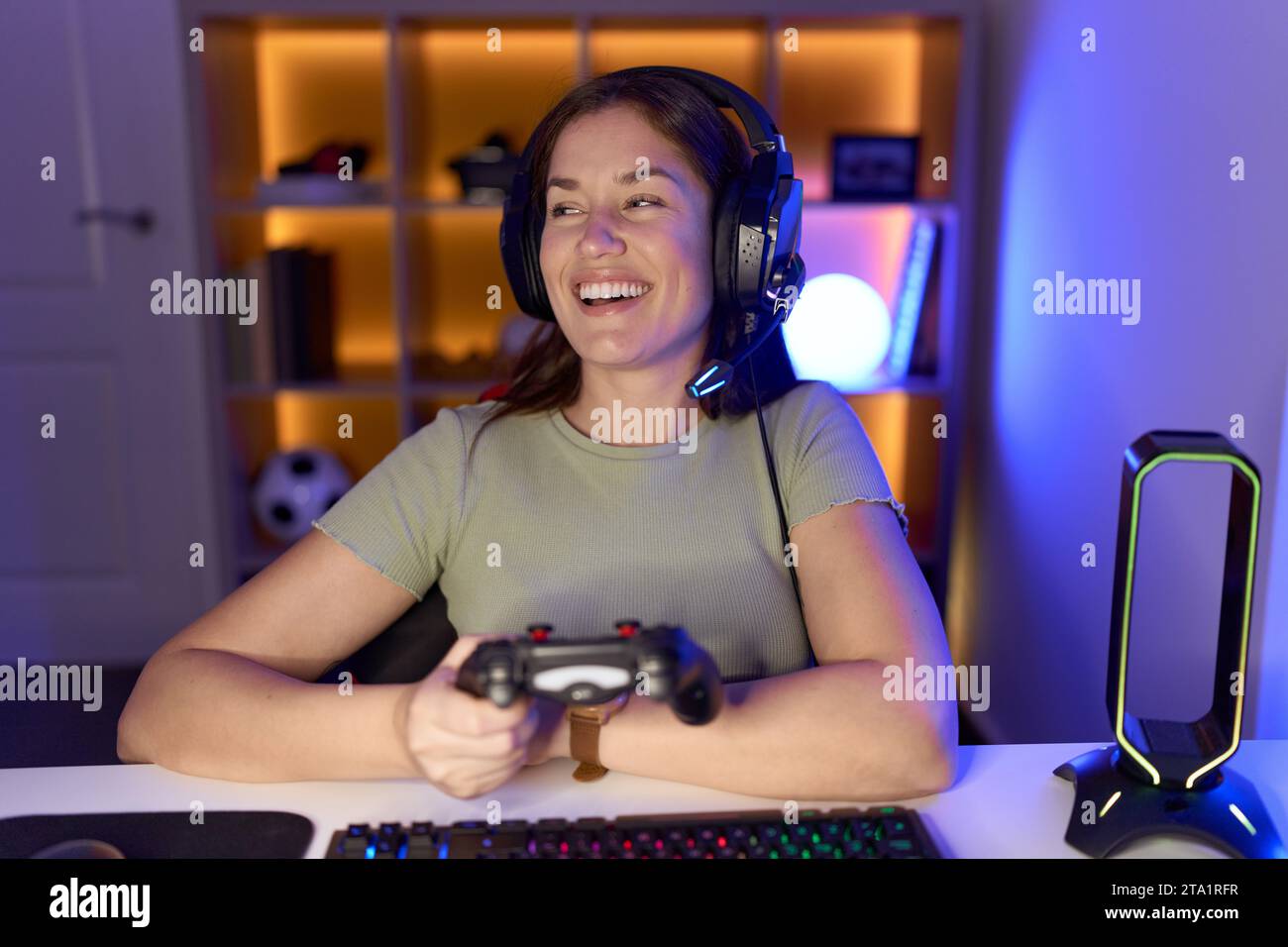 Beautiful brunette woman playing video games wearing headphones looking ...