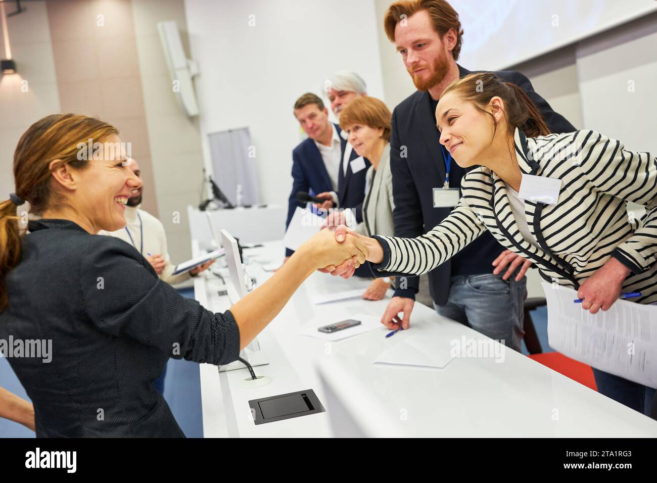 Smiling businesswoman handshaking with female audience at stage during ...