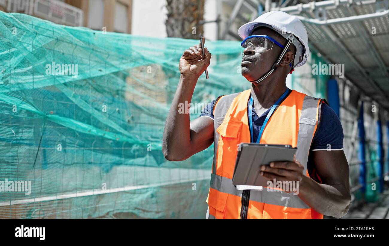 African american man builder using touchpad looking around at ...
