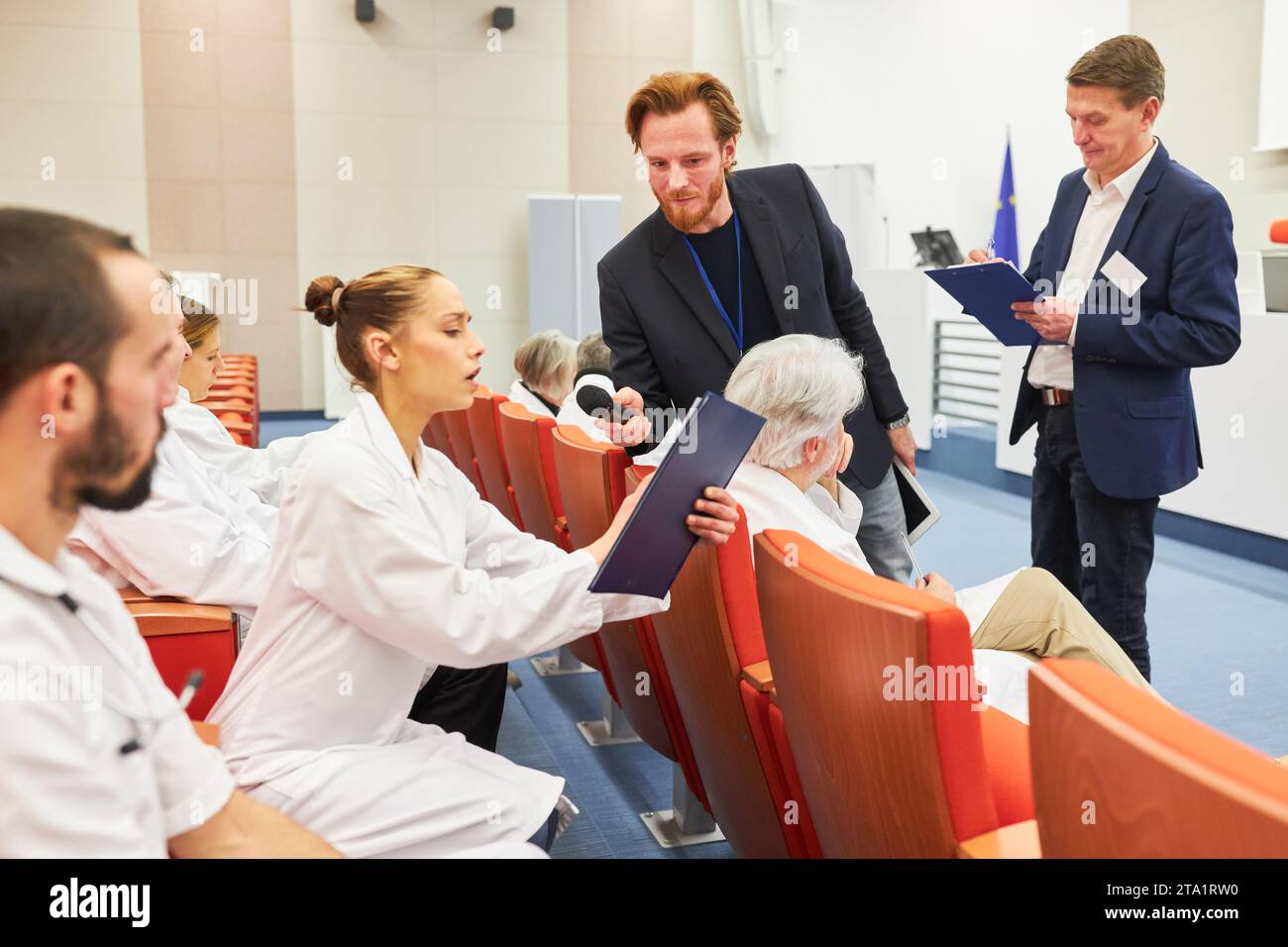 Female doctor in audience of medical conference asking question to ...