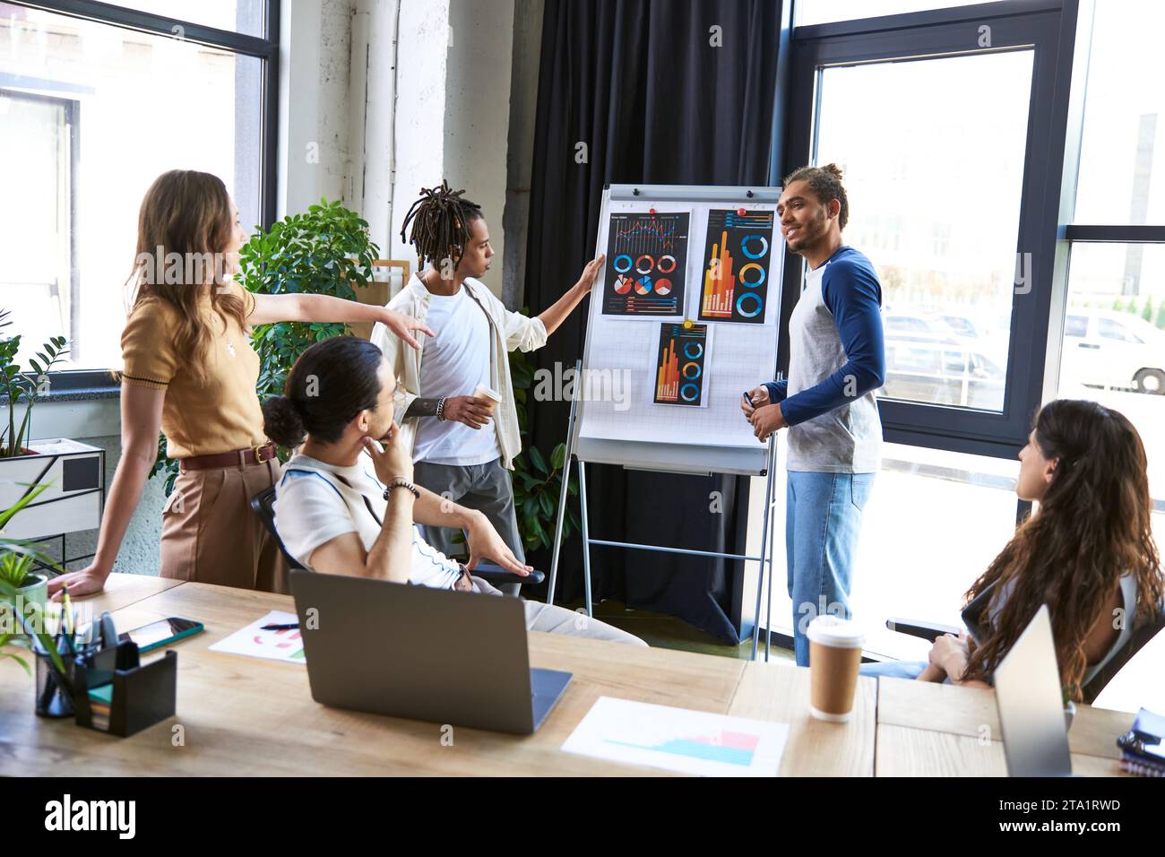 businesswoman pointing at flip chart with graphs near multiethnic team ...