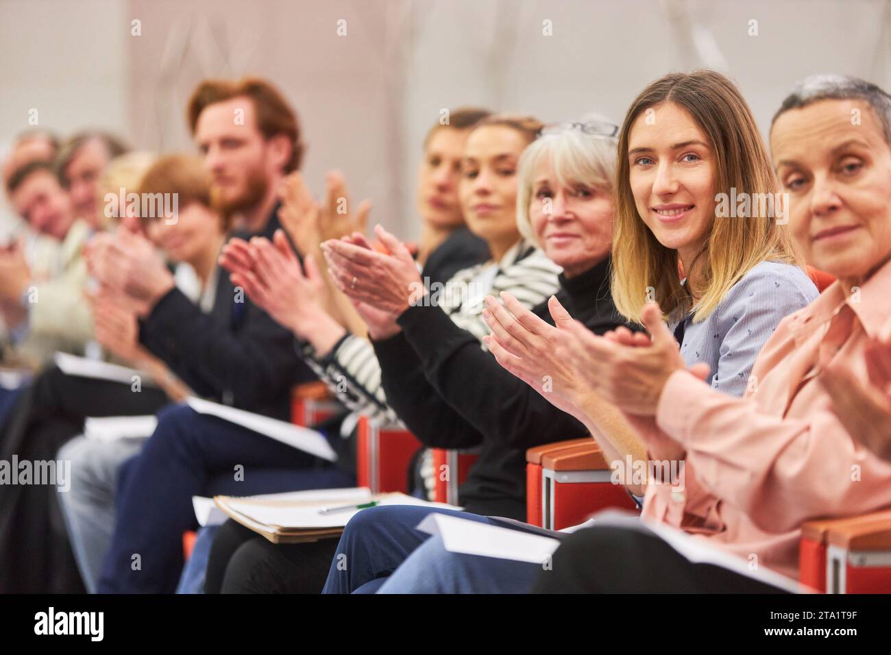 Portrait of smiling audience applauding while sitting at business event ...