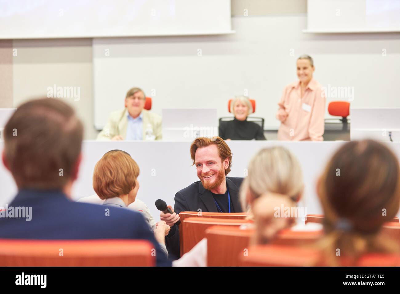 Smiling orator asking question to audience in conference at convention ...