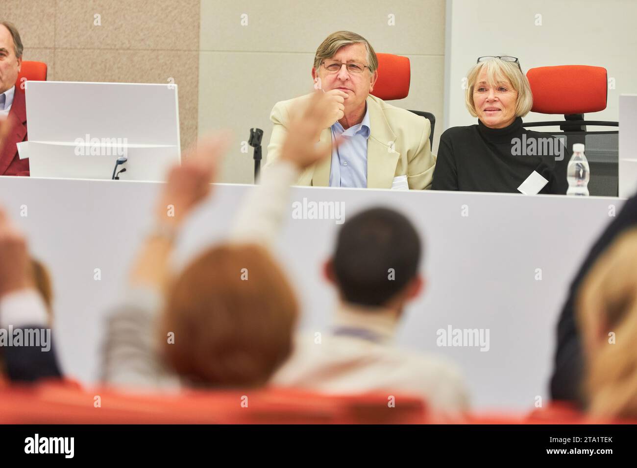 Male and female speakers at conference taking questions from raised ...