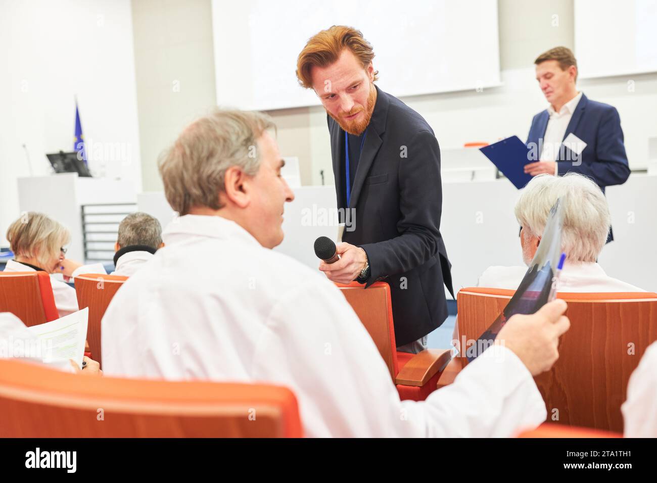 Male doctor in audience of medical conference asking question to ...